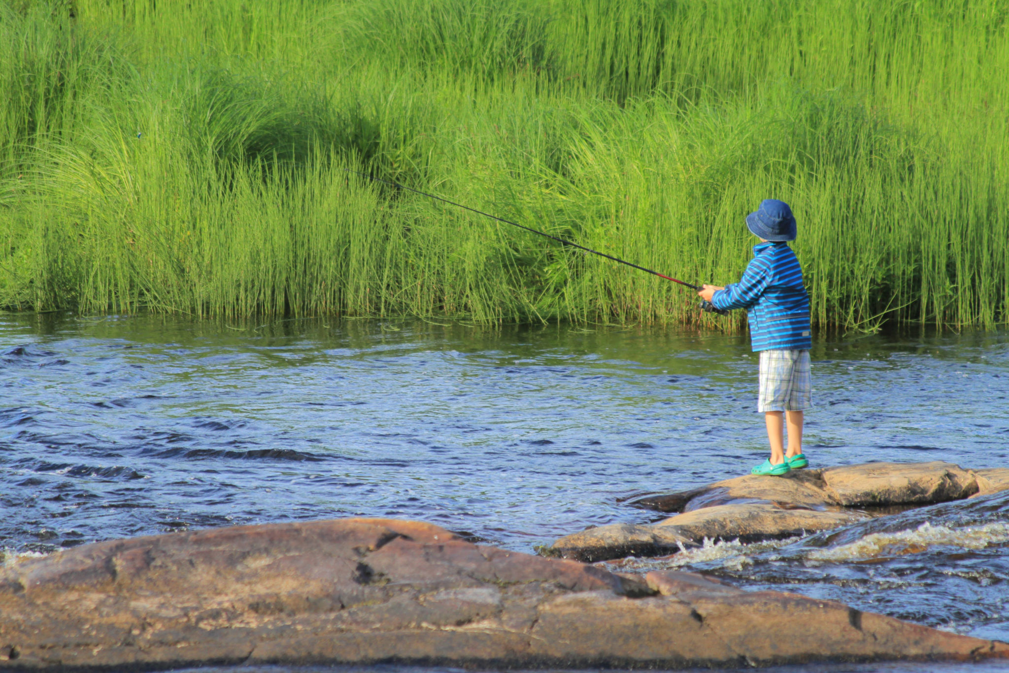 Kuva: pieni poika kalastaa kosken rannalla - Koiteli, Oulu - Visual Finland